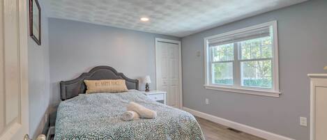 Um quarto com uma cama, uma janela e uma porta.