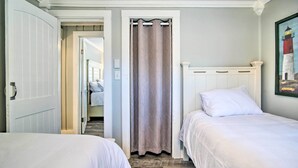 Quarto de hotel com duas camas, banheiro com cortina de chuveiro e um quadro na parede.