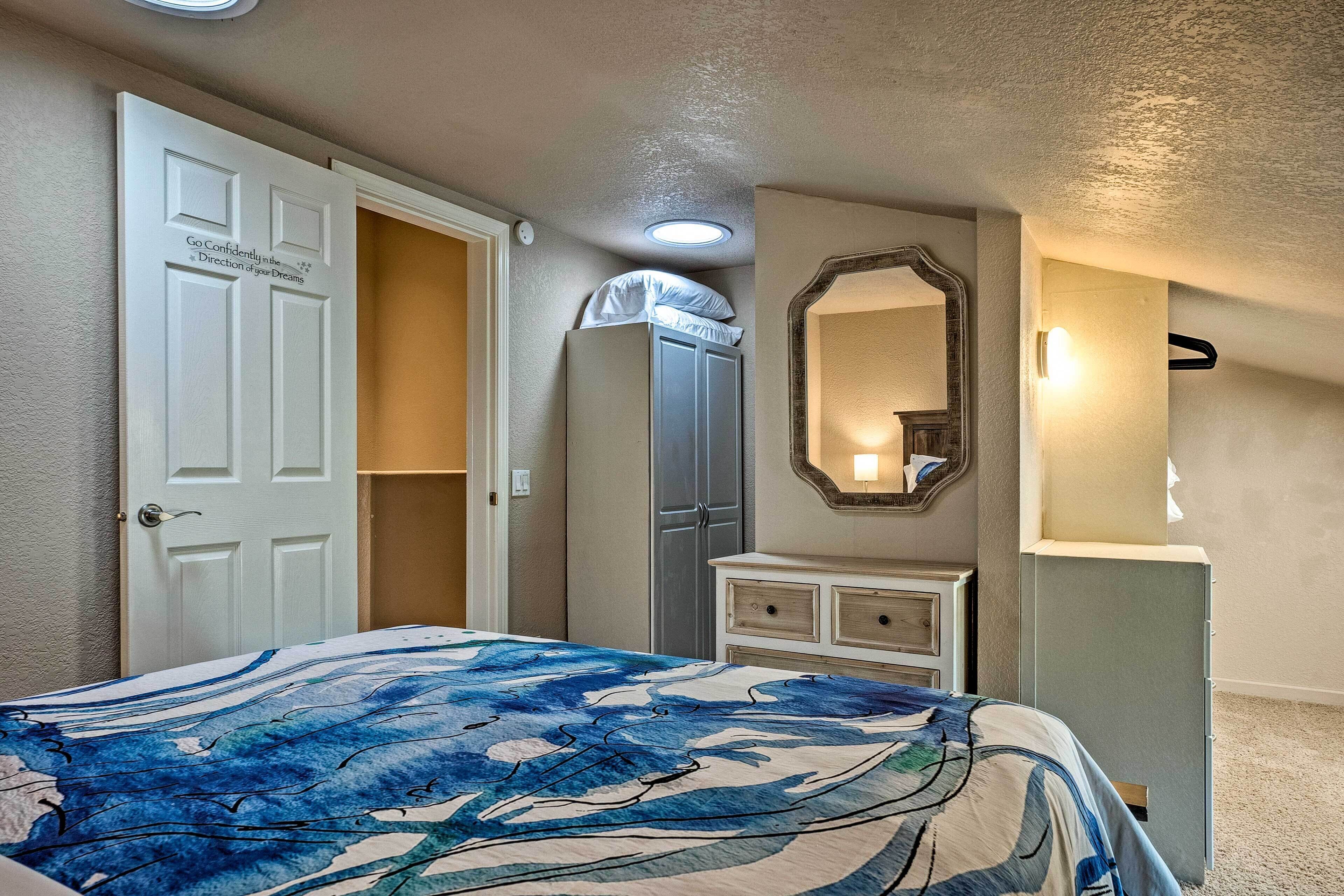 Quarto com cama, guarda-roupa, cômoda, espelho e porta com mensagens motivacionais.