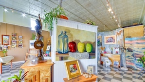 Um quarto com piso xadrez, móveis de madeira e diversas obras de arte expostas nas paredes e prateleiras.