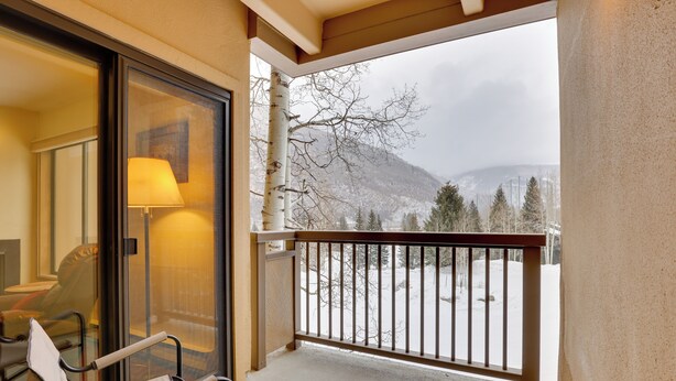 Varanda com vista para montanhas cobertas de neve e árvores sem folhas.