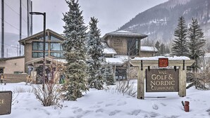 Entrada coberta de neve para um clube de golfe e centro nórdico, com um letreiro indicando uma churrasqueira no alpendre.