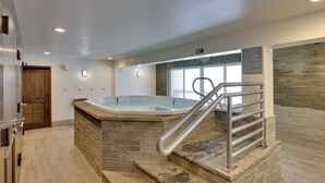 Uma área de spa com hidromassagem, porta de madeira e parede de pedra.