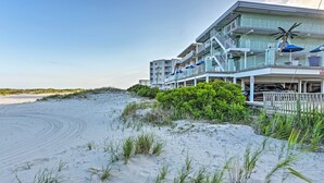Um hotel na praia com várias varandas, uma palmeira e uma praia de areia.