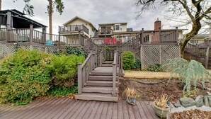 Um deck de madeira que leva a uma casa com varanda coberta e escada.