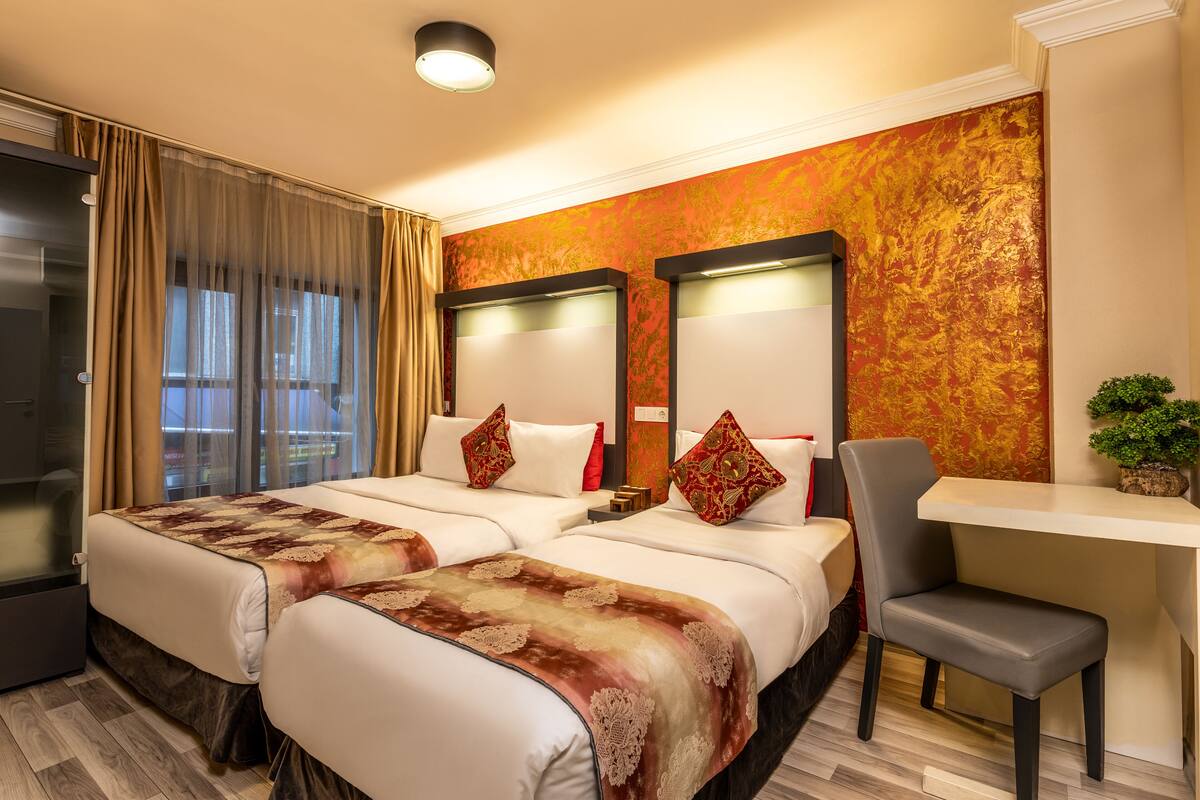Quarto de hotel com duas camas, uma escrivaninha e uma cadeira.