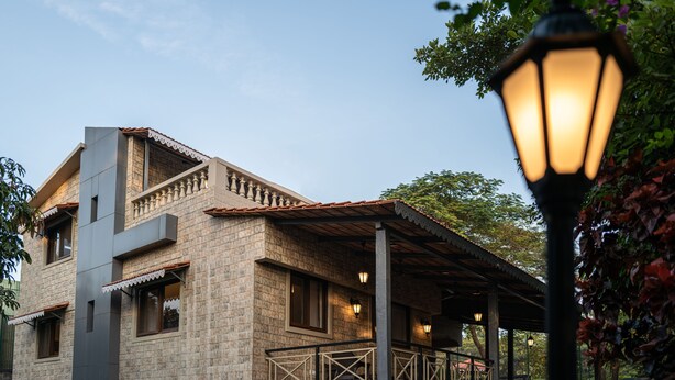 Um edifício de dois andares com fachada de tijolos, varanda com guarda-corpo e área de varanda coberta.