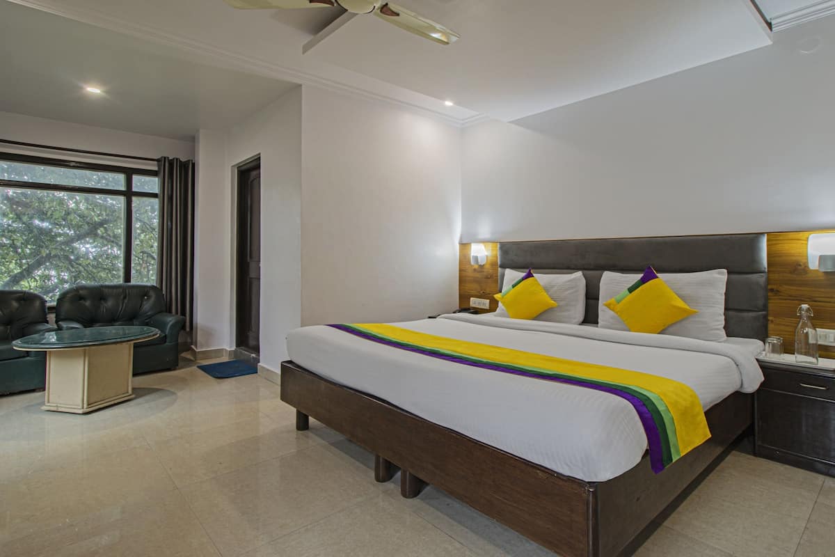 Quarto de hotel com uma cama grande, mesa de cabeceira, escrivaninha e uma cadeira.