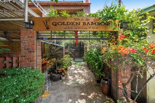 Placa para Golden Bamboo, uma villa e spa, com entrada de tijolos e plantas em vasos.