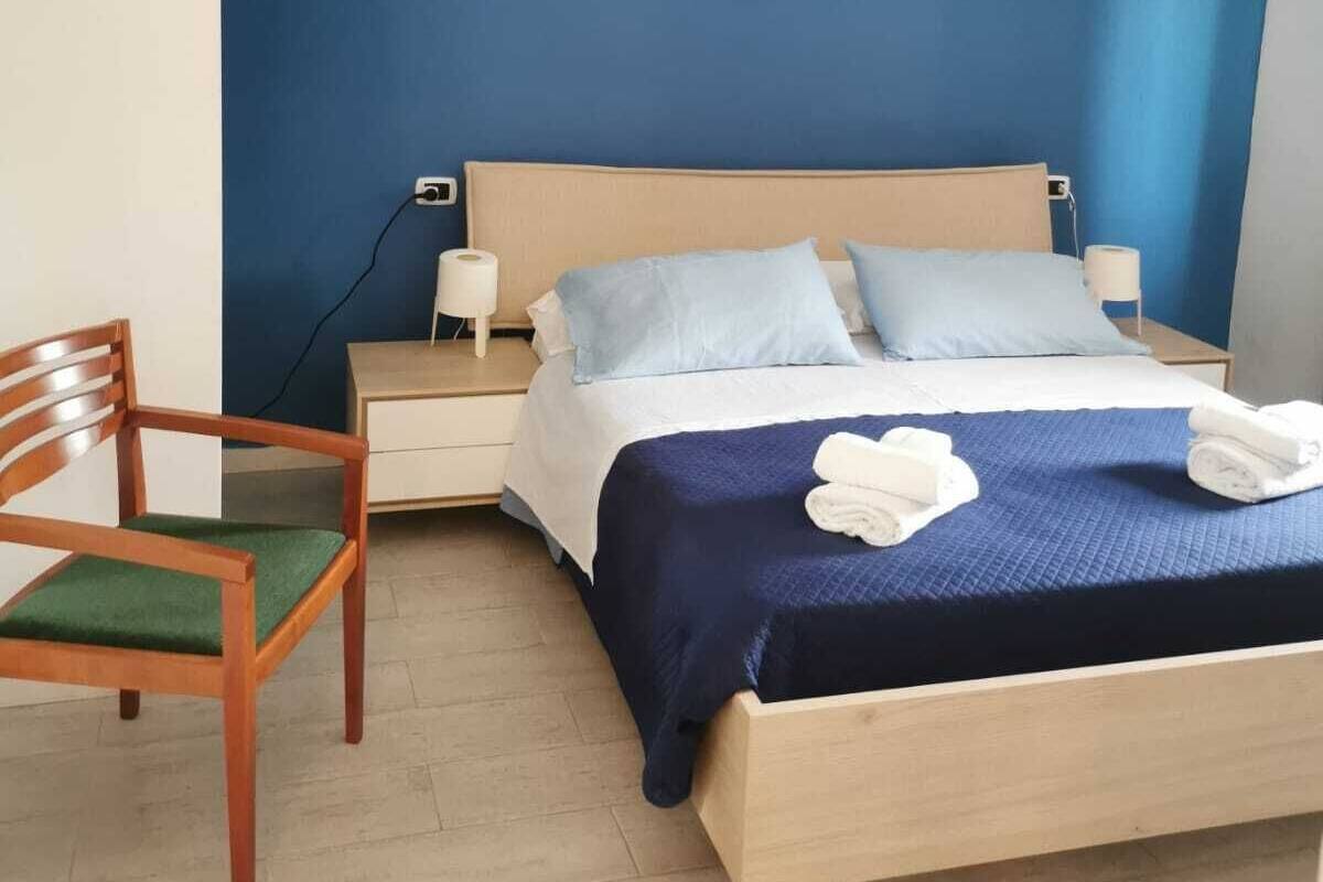 Quarto com cama, mesas de cabeceira, uma cadeira e unidade de ar condicionado na parede.