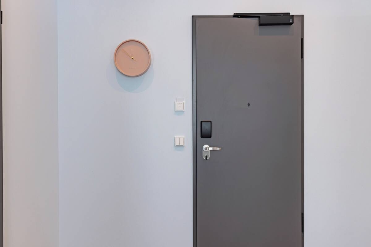 Uma porta com fechadura, um interruptor de luz na parede e um relógio.