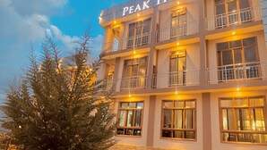 Um hotel de vários andares com varandas e uma placa com a inscrição 'PEAK HOTEL'.