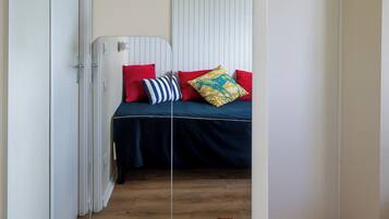 Quarto com cama, espelho, guarda-roupa e um pequeno estrado de madeira.