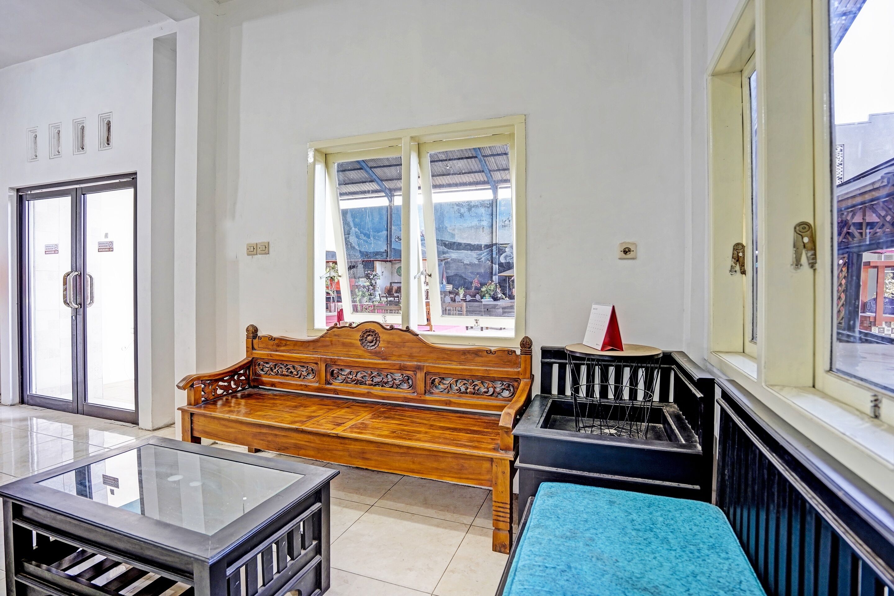 Quarto com um banco de madeira, uma mesa com tampo de vidro e um banco estofado azul.