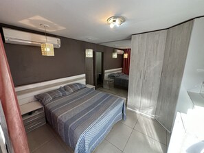 Quarto com cama, mesas de cabeceira, guarda-roupa e espelho.
