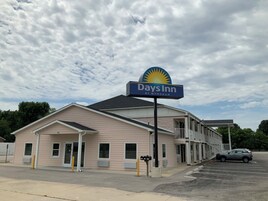 Um Days Inn by Wyndham com estrutura em um único andar, varanda coberta e estacionamento.