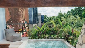 Um terraço no telhado com hidromassagem, mobiliário de madeira e vegetação exuberante.