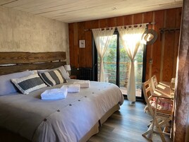 Quarto com cama grande, cabeceira de madeira e área de refeições com mesa e cadeiras.