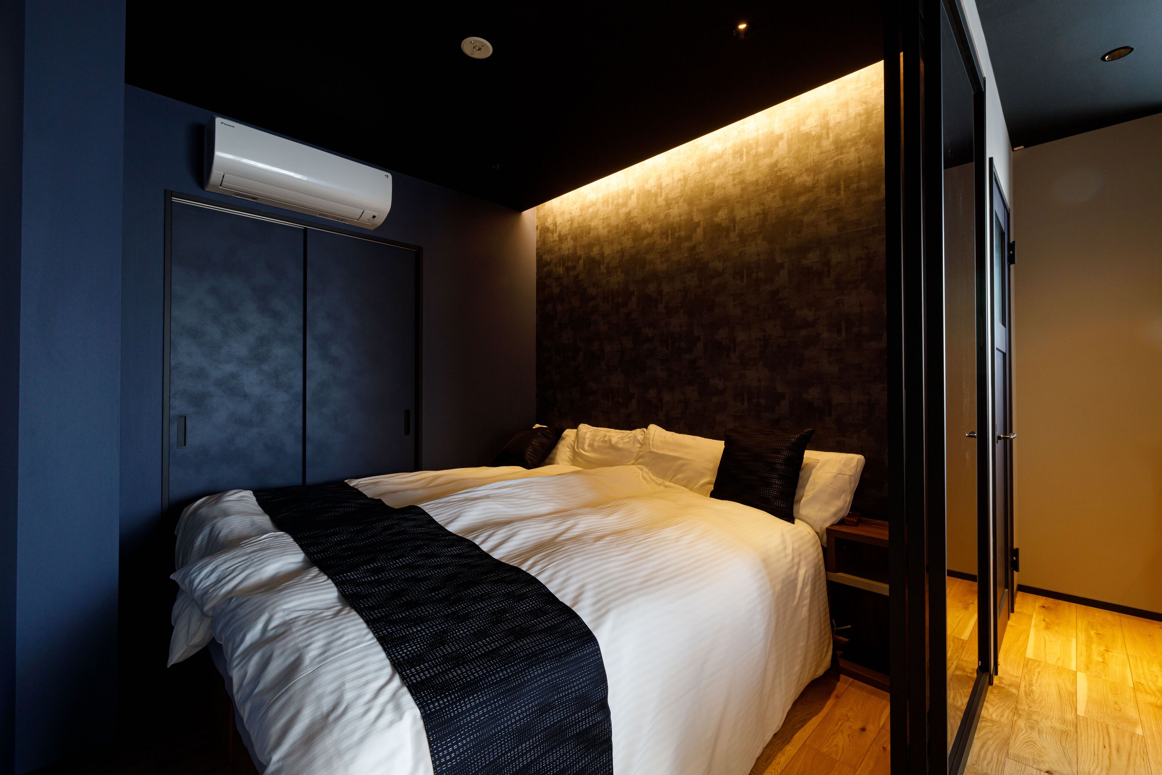 Quarto moderno com cama grande, armário embutido e ar condicionado fixado na parede.