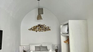 Quarto minimalista com uma cama, luminária pendente e prateleira fixada na parede.