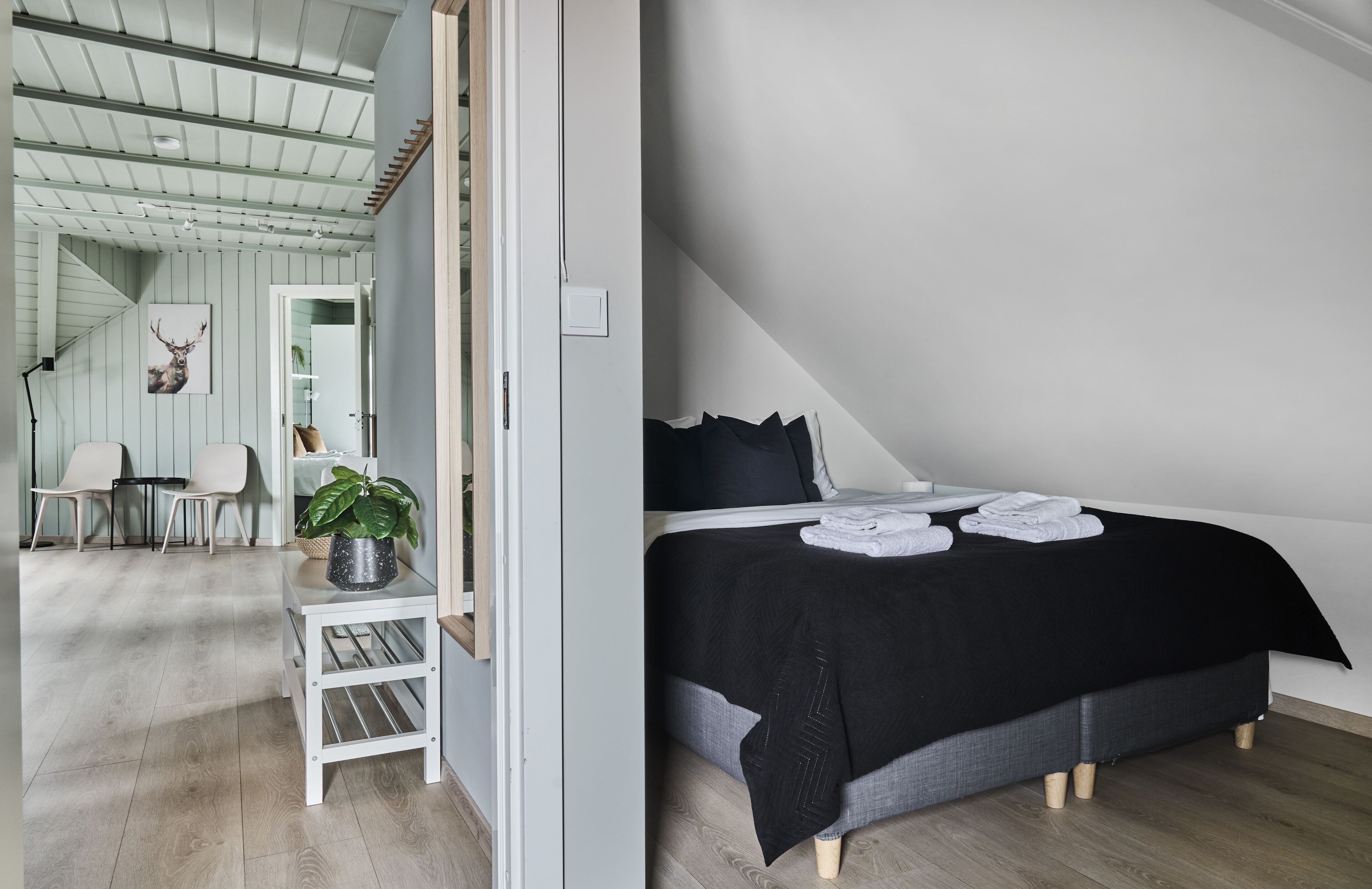 Quarto moderno com cama, uma mesinha com uma planta e uma cadeira.