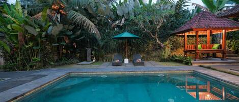 Uma área de piscina com espreguiçadeiras e um gazebo.