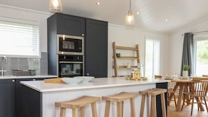 Uma cozinha moderna com armários escuros, eletrodomésticos de aço inoxidável e banquetas de madeira.