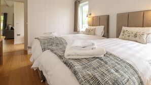 Quarto de hotel com uma cama grande, duas almofadas, um cobertor e uma janela com cortinas.