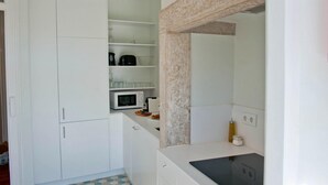Cozinha compacta com armários brancos, micro-ondas e bancada pequena.