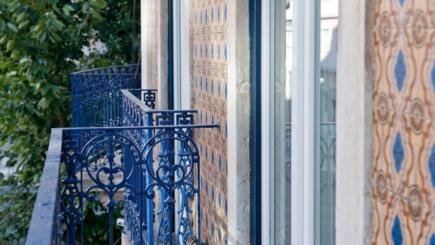 Fachada de edifício com grades de metal ornamentadas e azulejos padronizados.