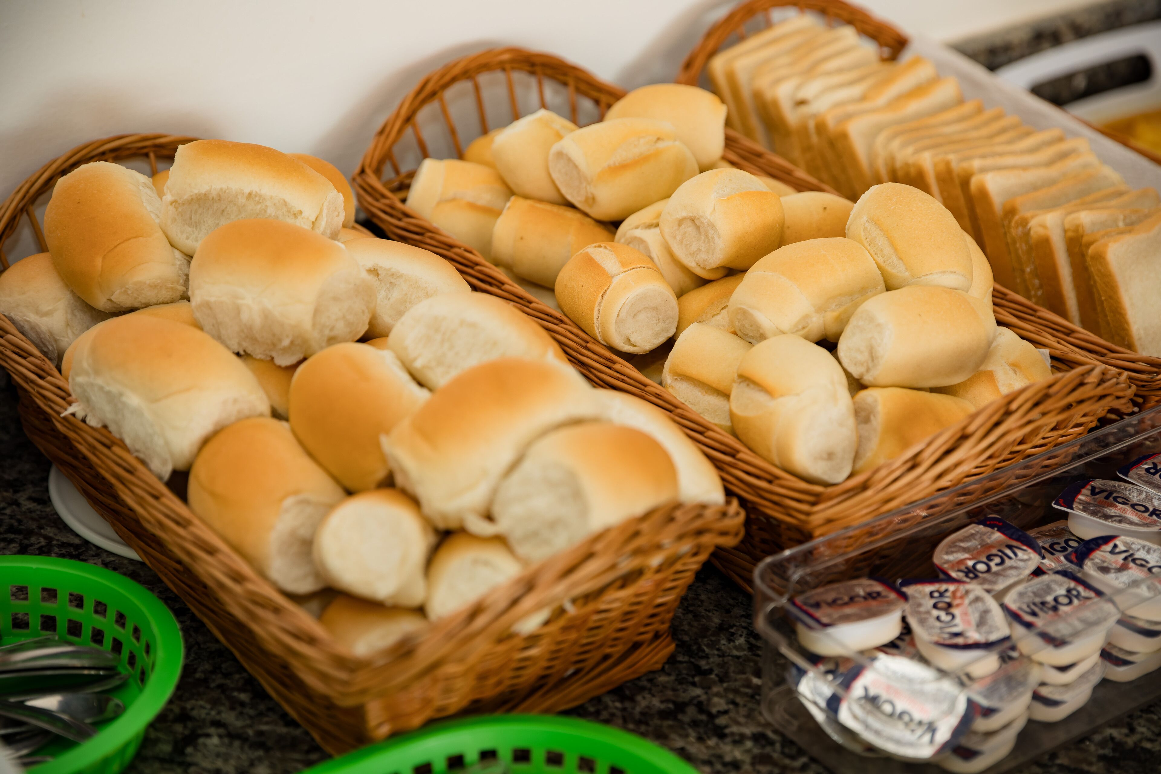 Cestos com pães e embalagens de manteiga sobre um balcão.
