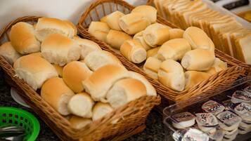 Cestos com pães e embalagens de manteiga sobre um balcão.
