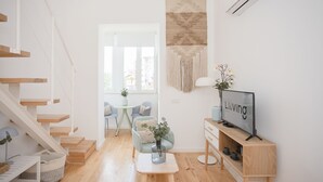 Uma sala de estar moderna com escada, televisão e área de jantar.