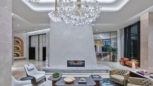 Uma sala de estar moderna com lareira, assentos confortáveis e um lustre grande.