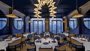 Uma sala de jantar moderna com mesas redondas, cadeiras de vime e um lustre de design exclusivo.