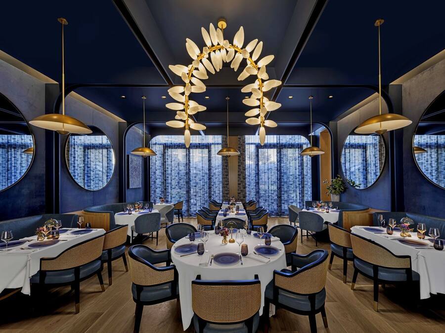 Uma sala de jantar moderna com mesas redondas, cadeiras de vime e um lustre de design exclusivo.