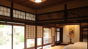 Um quarto em estilo japonês tradicional, com piso de tatame, futon baixo, portas deslizantes shoji e vista para um jardim.