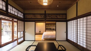 Um quarto japonês tradicional com tatames, uma mesa baixa e uma cama.