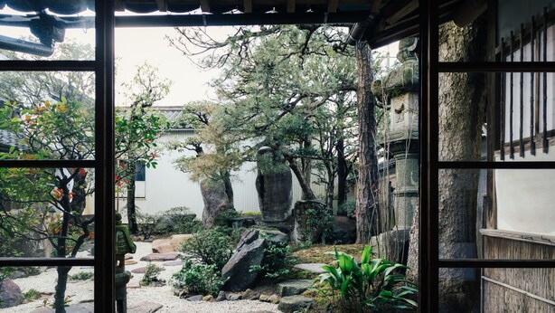 Um jardim japonês tradicional com um caminho de pedra, rochas e árvores.