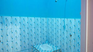 Casa de banho com chão quadriculado azul e branco, sanita branca e azulejos azuis com padrão floral.