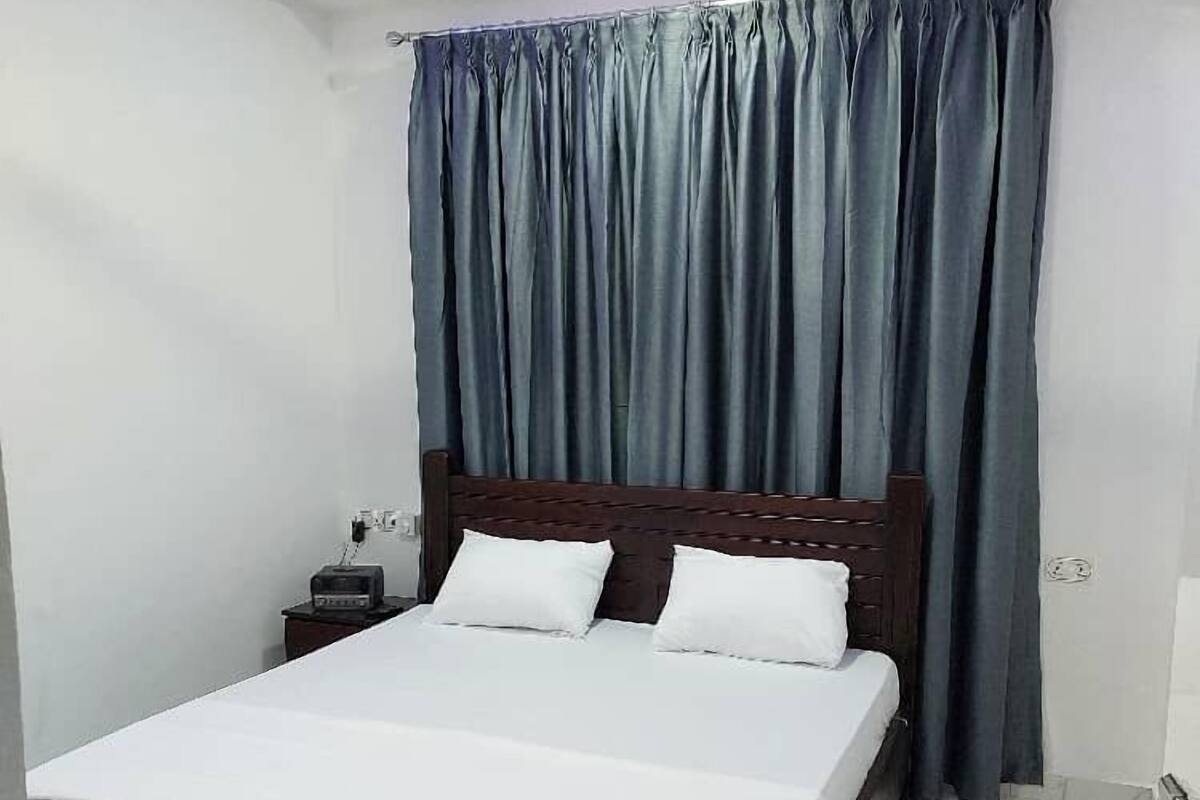 Quarto com cama, ventilador de teto e mesa de cabeceira.