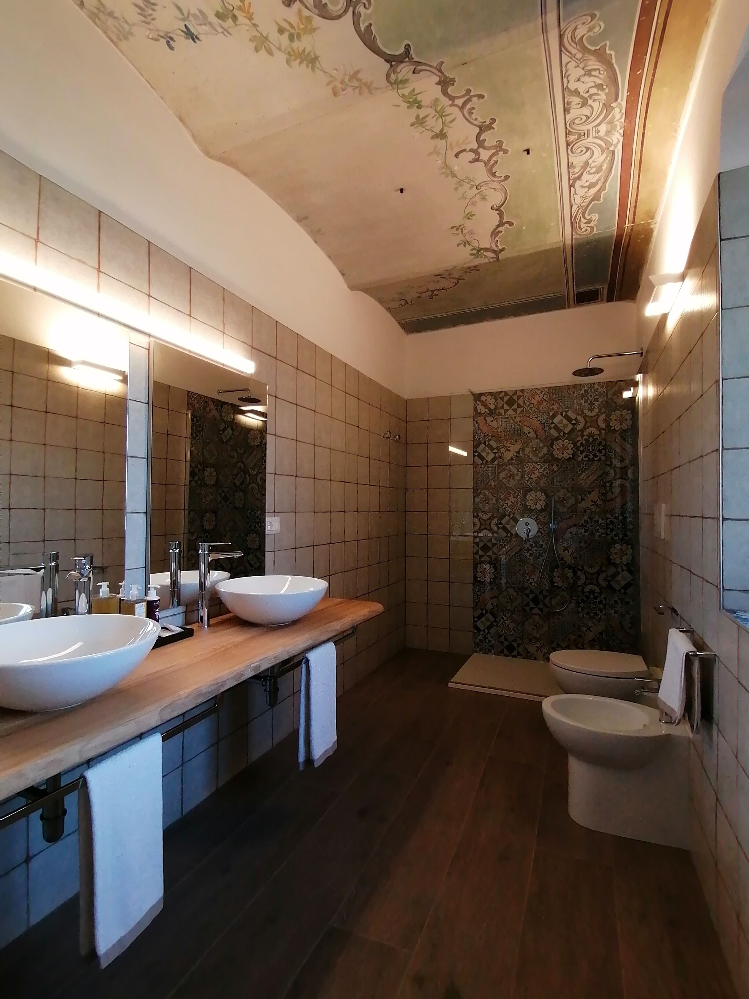 Uma casa de banho moderna com duas lavatórios, uma sanita e um chuveiro.