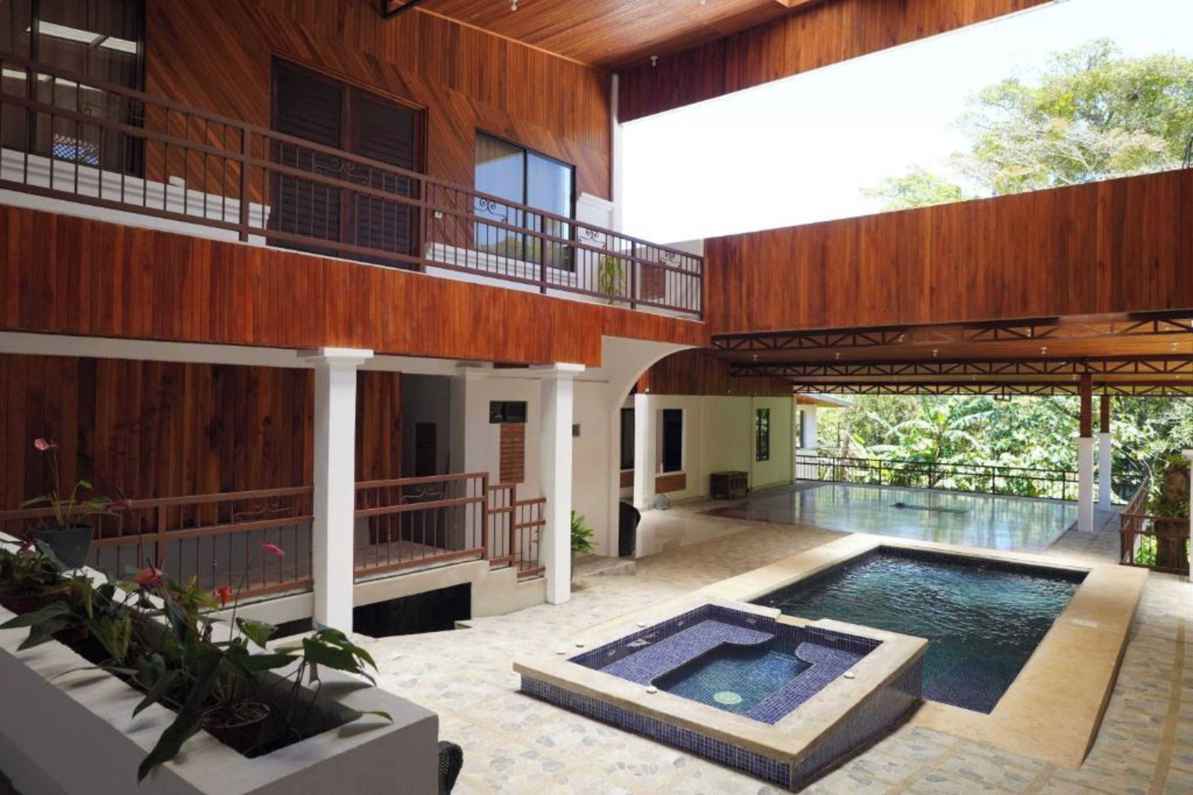 Amplo espaço interno com uma piscina grande, arquitetura de madeira e uma varanda.