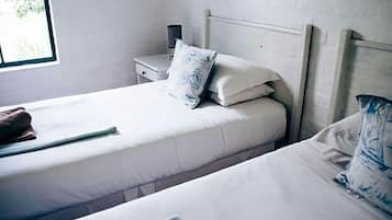 Quarto com cama, mesa de cabeceira e janela.