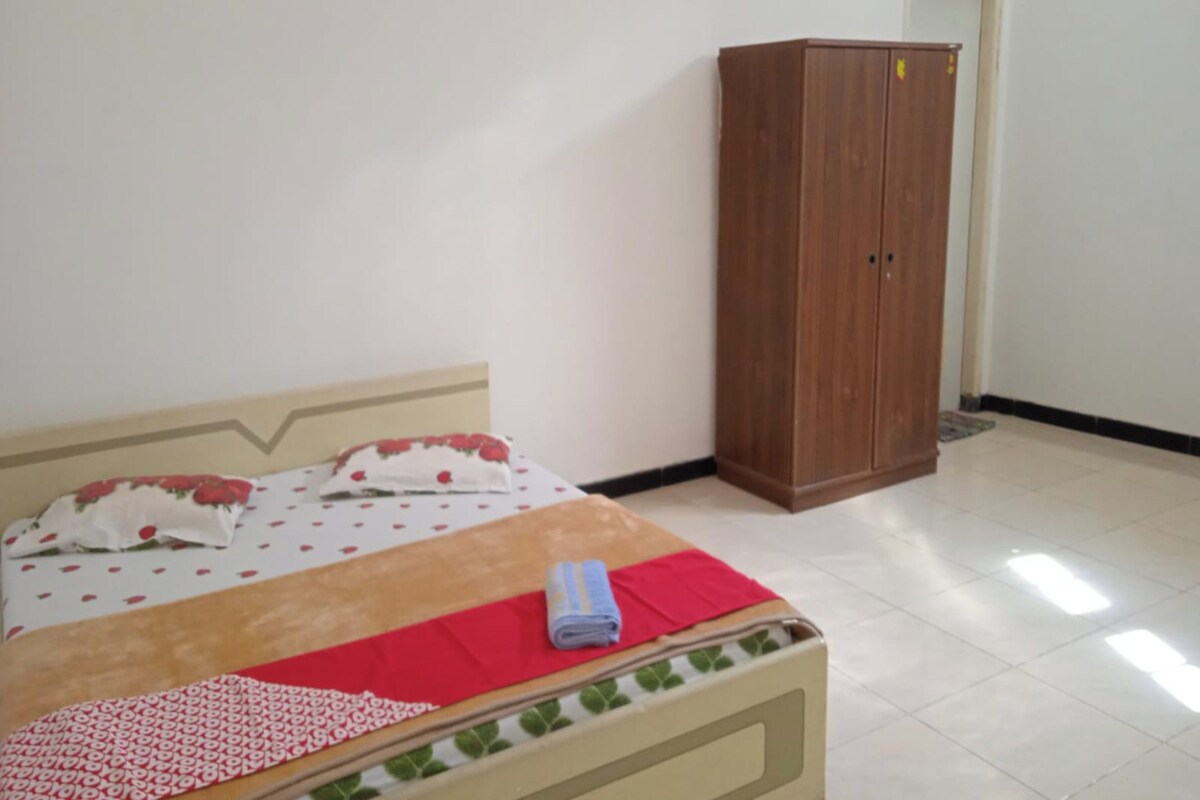 Quarto com cama, guarda-roupa de madeira e soalho em azulejos.