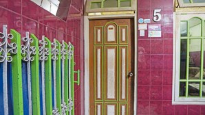 Entrada de um edifício com porta de madeira, placa com o número 5 e janela com molduras verdes.