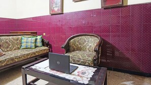 Um quarto com um sofá estampado, uma cadeira de madeira e um laptop sobre uma mesa.