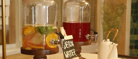 Uma área de bar com dois dispensadores de bebidas, uma placa com a inscrição 'DEJON WATER' e uma chaleira branca.