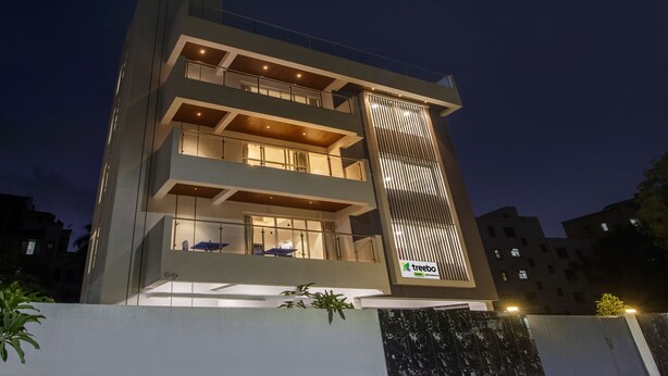 Um edifício de vários andares com sacadas, uma placa visível com 'treebo' e um design arquitetônico moderno.