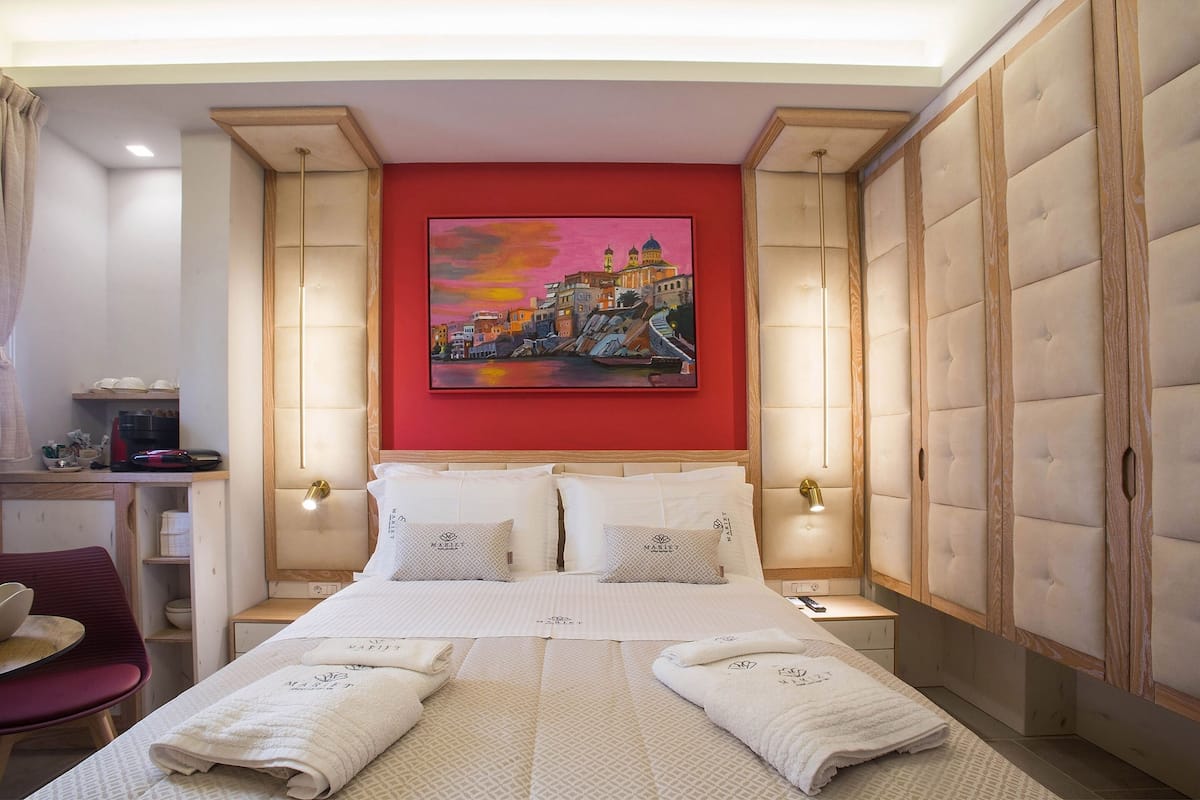 Quarto de hotel com uma cama grande, duas mesas de cabeceira, uma escrivaninha e uma cadeira.